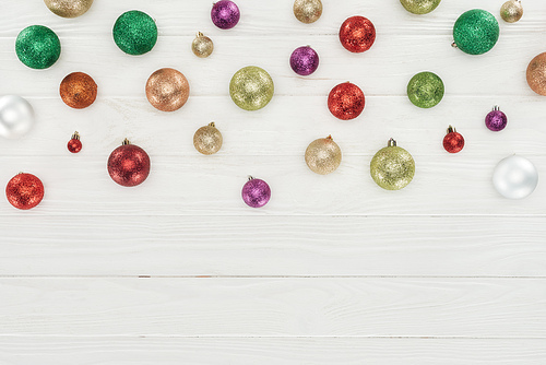 top view of beautiful shiny colorful christmas balls on white wooden ...