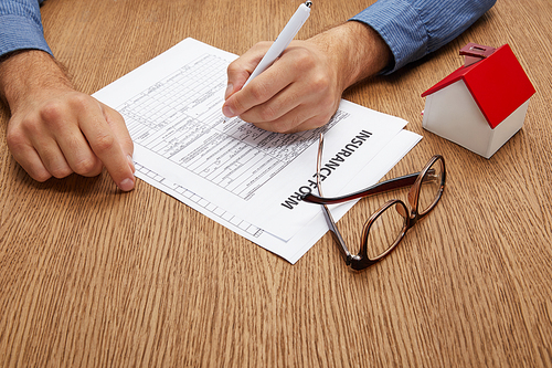 유토이미지 | cropped shot of person signing insurance form at wooden table