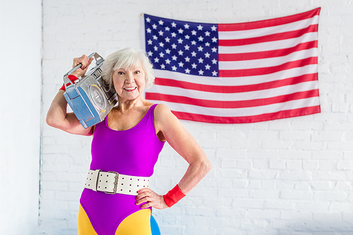 happy senior sportswoman holding tape recorder and smiling at camera ...