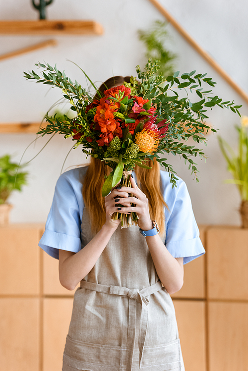 young florist in apron hiding face behind beautiful flower bouquet | 유토 ...