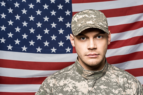 유토이미지 | handsome soldier in military uniform and cap near flag of america
