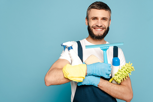 happy cleaner in uniform and rubber gloves holding cleaning supplies on ...