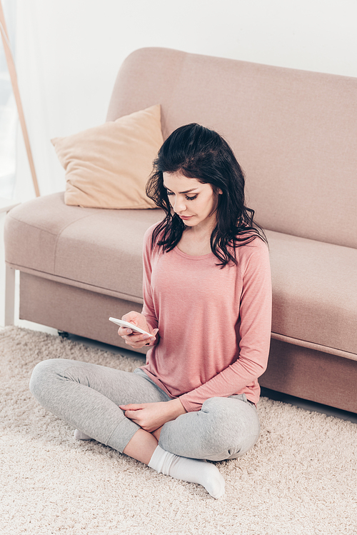 beautiful woman sitting on carpet and using smartphone in Living Room ...
