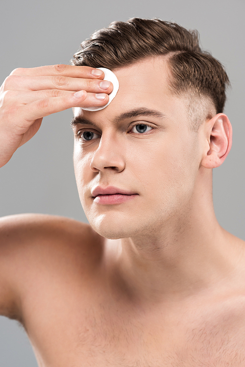 handsome young man wiping face with cotton pad isolated on grey | 유토이미지 ...