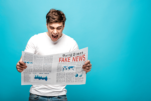 angry man yelling while reading newspaper with fake news on blue ...