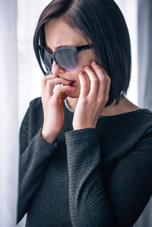 유토이미지 | depressed woman in sunglasses covering mouth and grieving at home