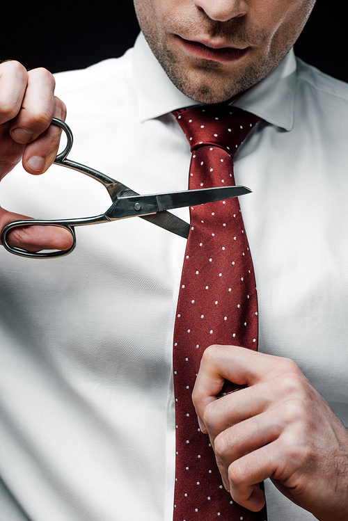 유토이미지 | cropped view of displeased businessman cutting tie with scissors isolated on black