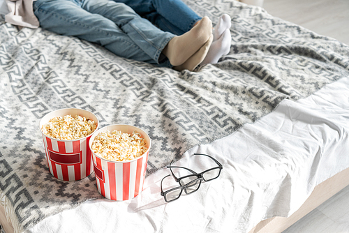 유토이미지 | Cropped view of couple lying on bed beside popcorn buckets and 3d glasses