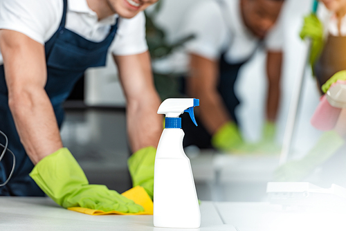 cropped view of cleaner wiping office desk near spray bottle with ...