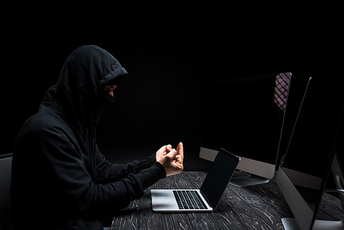 displeased hacker showing middle finger near laptop and computer ...
