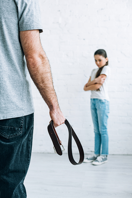 cropped view of father holding belt and upset daughter at home | 유토이미지 ...