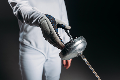 Cropped view of fencer in fencing suit and glove holding rapier ...