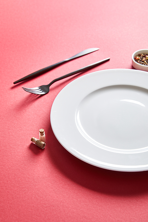 유토이미지 | empty round plate with cutlery and pepper in bowl on red background