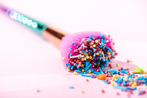 close up view of makeup brush covered in colorful sprinkles on pink ...