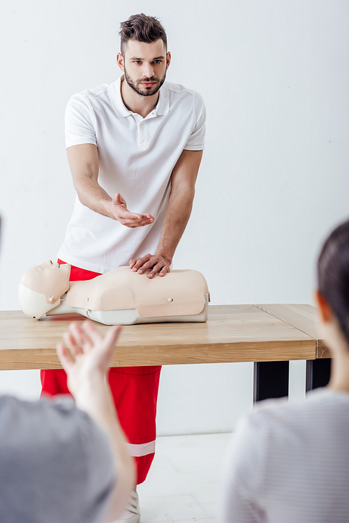handsome instructor with cpr dummy gesturing during first aid training ...