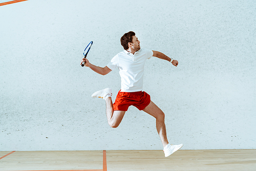 Sportsman in polo shirt jumping while playing squash in four-walled ...