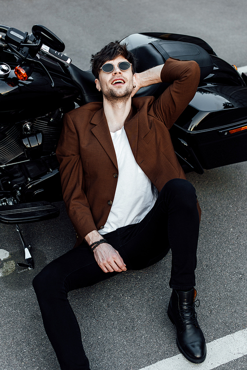handsome man sitting on ground smiling and resting while leaning head ...