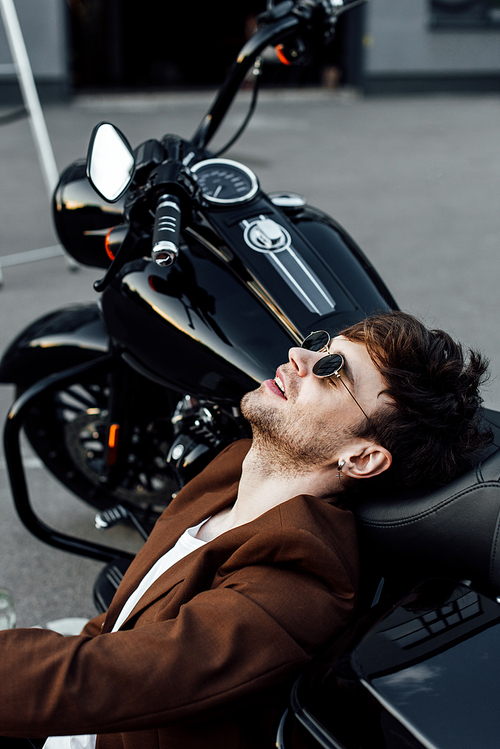 handsome motorcyclist in brown jacket resting while leaning head on ...