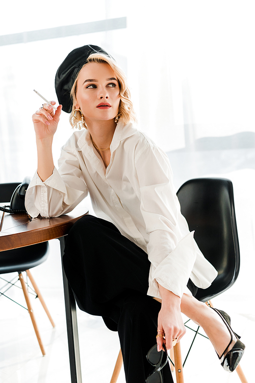 elegant blonde woman in black beret sitting on chair in pose and ...