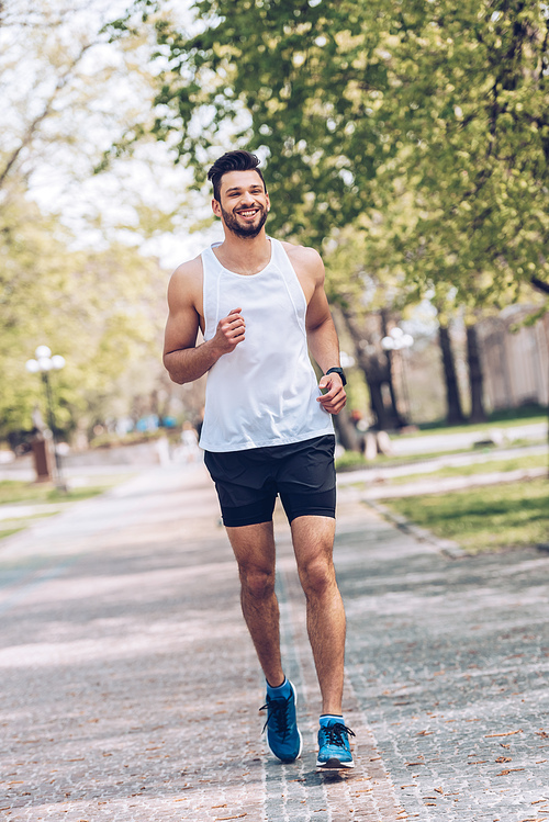 유토이미지 | cheerful sportsman smiling while running along wide walkway in park