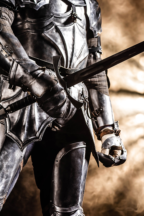 cropped view of knight in armor holding sword on black background | 유토 ...