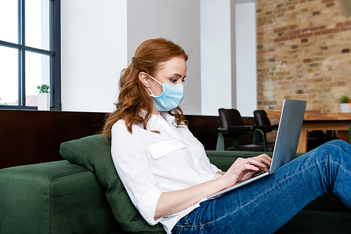 유토이미지 | Side view of teleworker in medical mask using laptop on couch