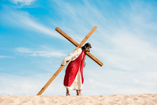 유토이미지 | bearded man in jesus robe walking with wooden cross against sky ...