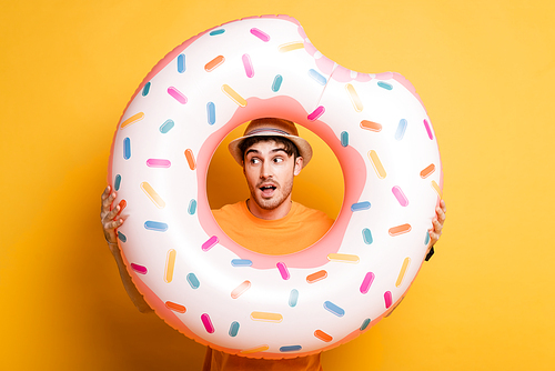 excited man with open mouth standing in hat with inflatable donut on ...