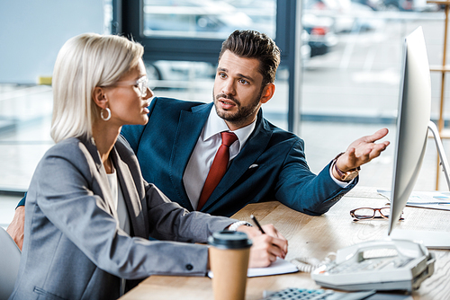 selective focus of handsome businessman looking at attractive coworker ...