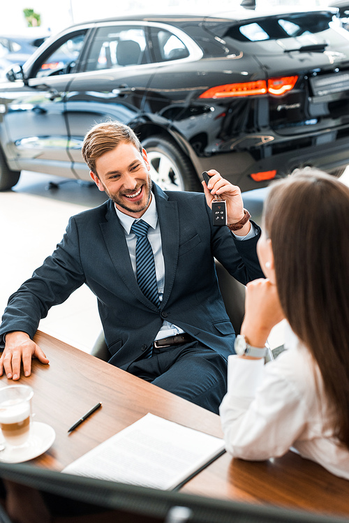 selective focus of cheerful bearded car dealer holding car keys near ...