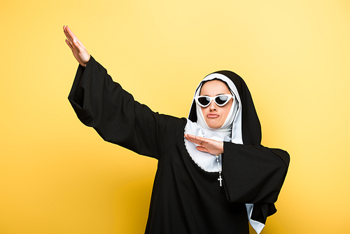 beautiful emotional nun gesturing in sunglasses on yellow | 유토이미지 | 상세 ...