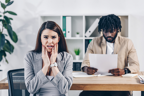 Scared employee and african american recruiter reading documents at ...