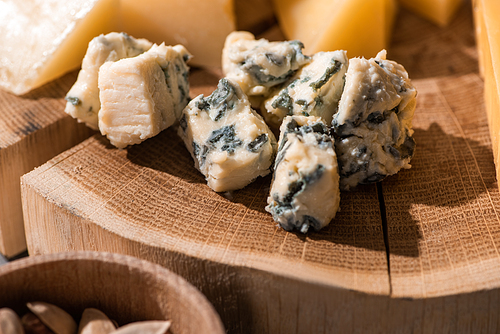 Selective focus of pieces of dorblu with grana padano on wooden board ...