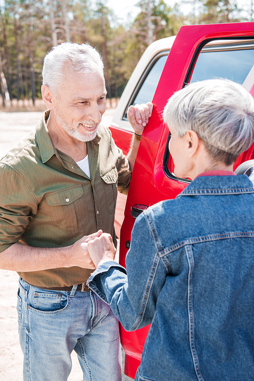 유토이미지 | smiling senior couple standing near red car, holding hands and ...