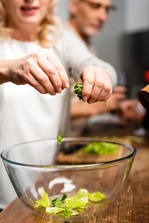 유토이미지 | cropped view of woman adding lettuce to bowl in kitchen