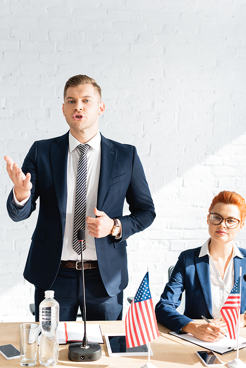 Confident politician gesturing, while talking, standing near smiling ...