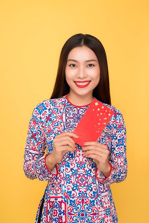 Pretty smiling Vietnamese woman with red envelopes isolated over yellow ...