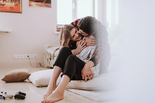 유토이미지 | Smil barefoot woman sitt on floor. Her man hugg and her in liv ...